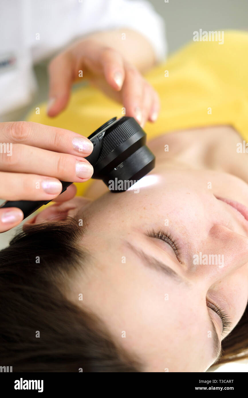 Female dermatologist using a professional dermatoscope while doing skin ...