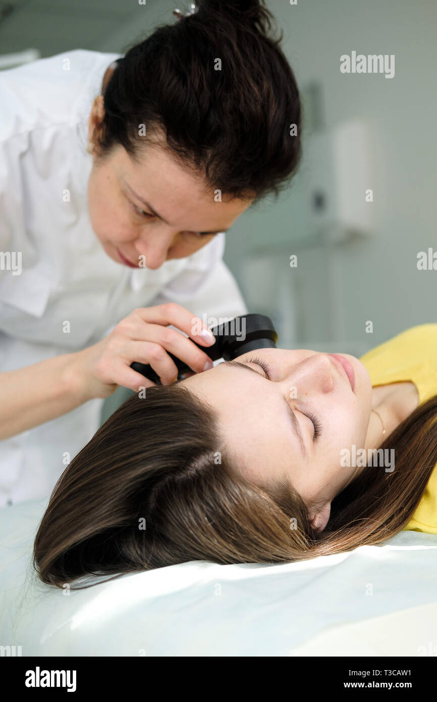 Female dermatologist using a professional dermatoscope while doing skin ...