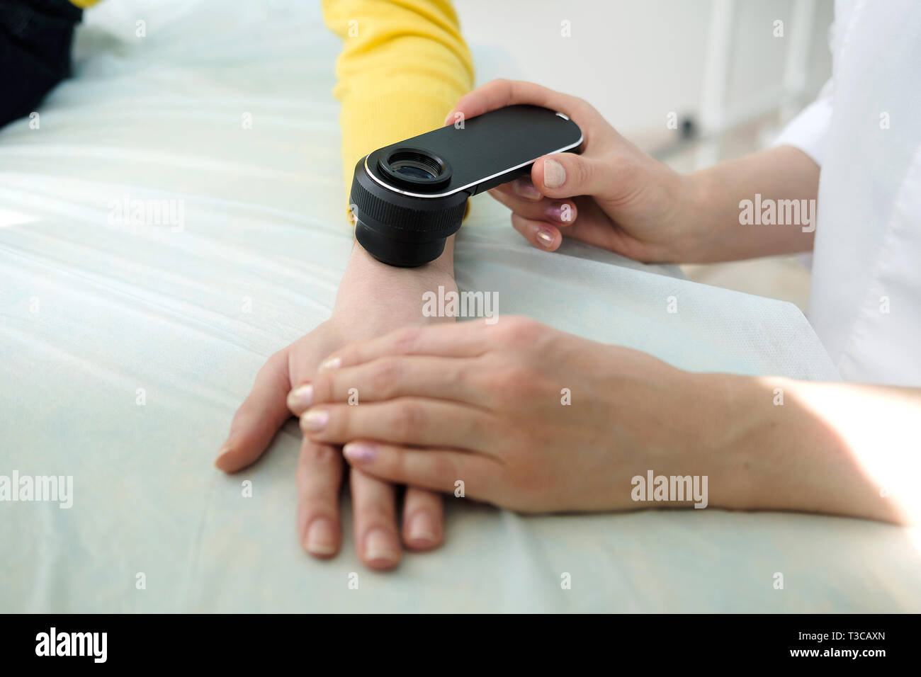 Female dermatologist using a professional dermatoscope while doing skin ...