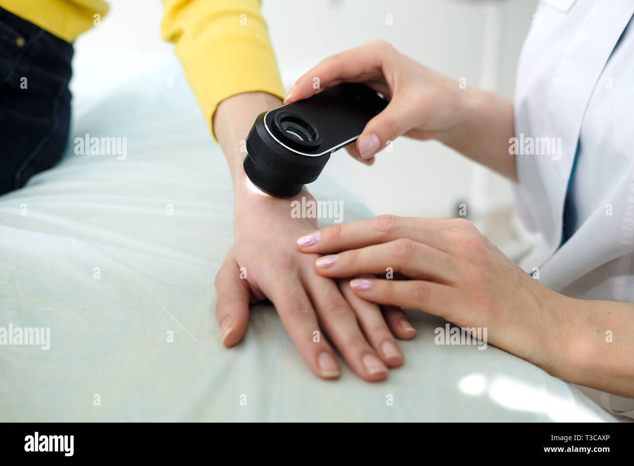 Female dermatologist using a professional dermatoscope while doing skin ...