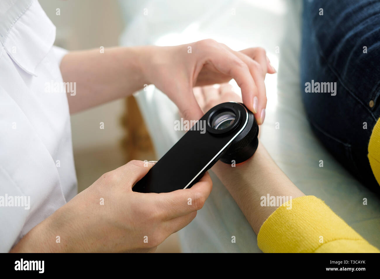Female dermatologist using a professional dermatoscope while doing skin ...