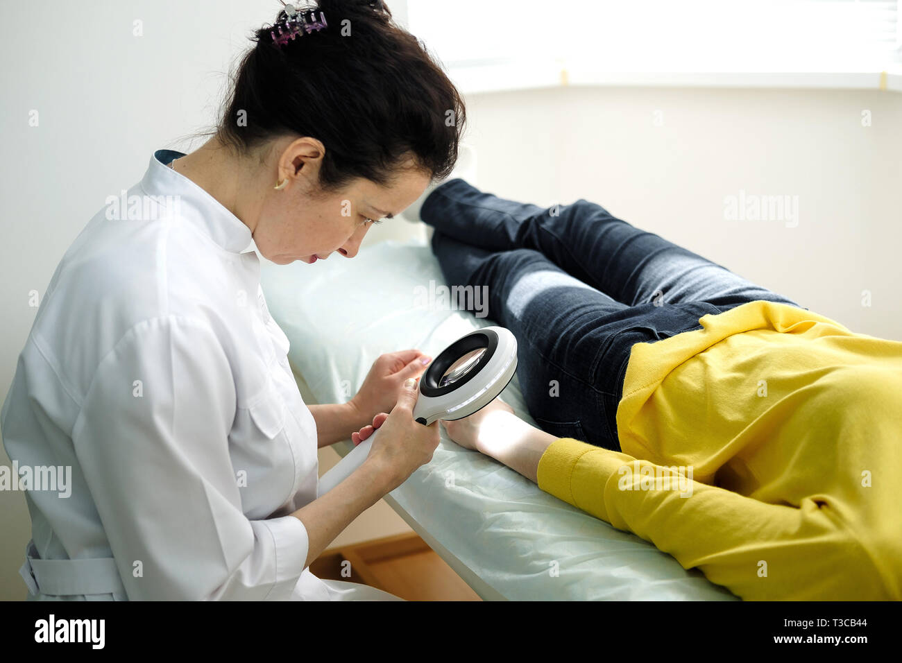 Dermatologist using a professional magnifying glass while doing skin ...