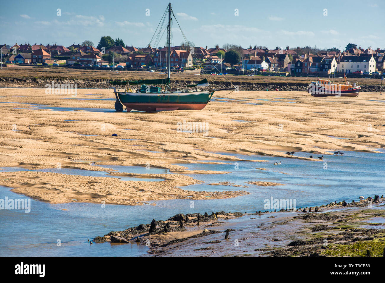 Colourful boats marooned on sandbanks at low tide on East Fleet river ...