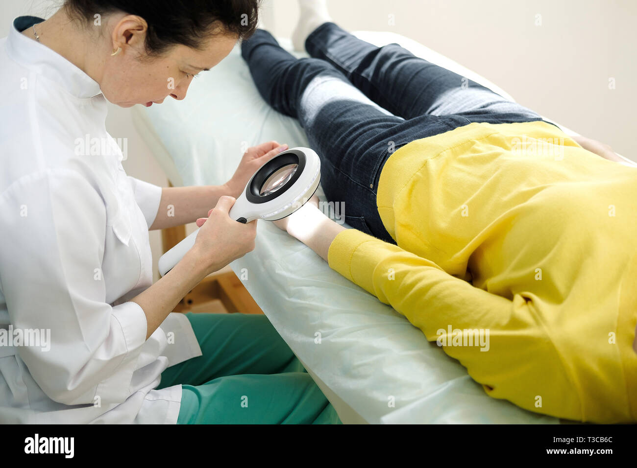 Dermatologist using a professional magnifying glass while doing skin ...