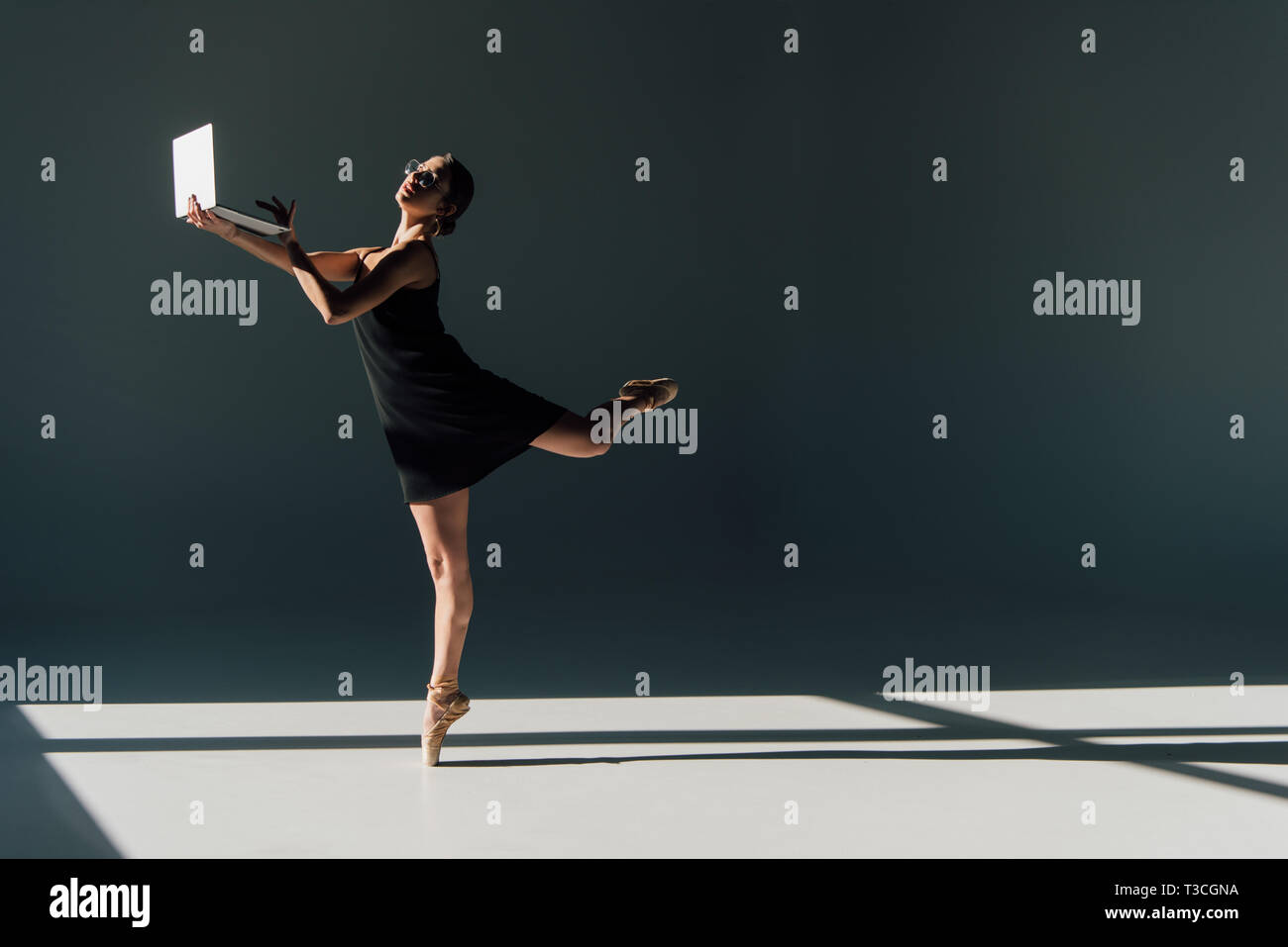 young ballerina in black dress and eyeglasses dancing with laptop Stock ...
