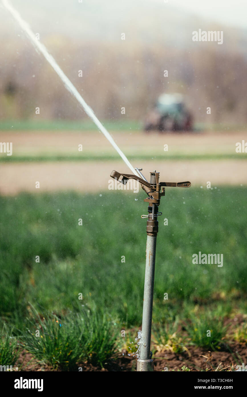 Irrigation plant on an agriculture field, tractor in the background ...