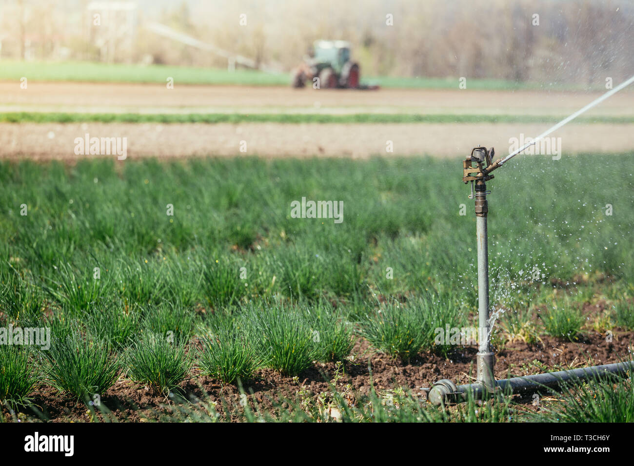 Irrigation plant on an agriculture field, tractor in the background ...