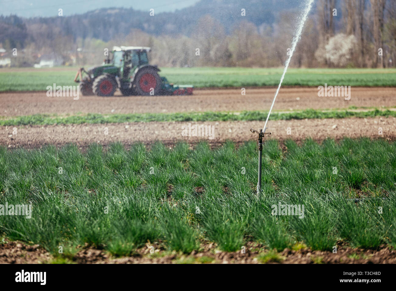 Irrigation plant on an agriculture field, tractor in the background ...