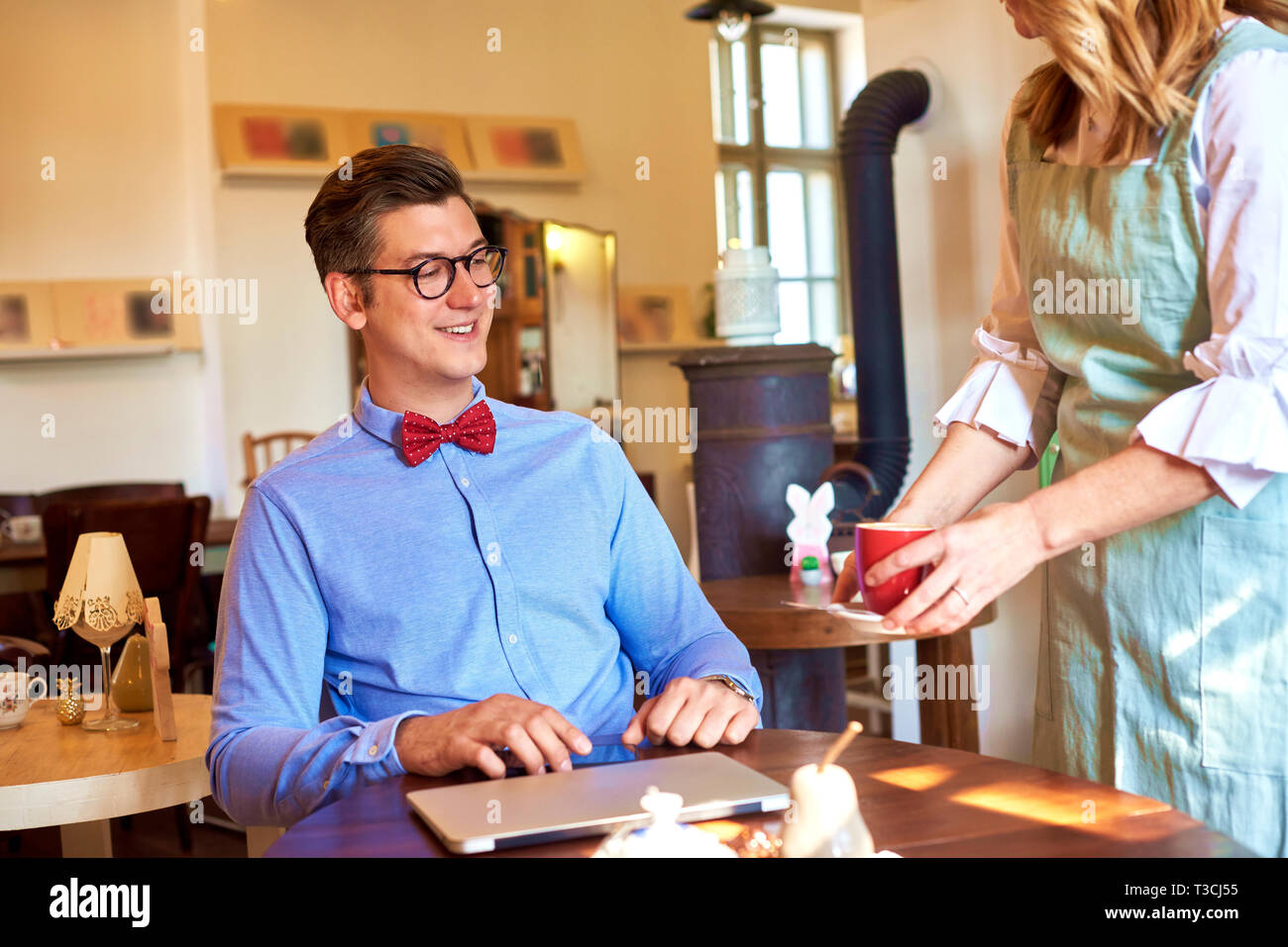 Portrait shot of young man sitting in cafe and waiting for waitress ...