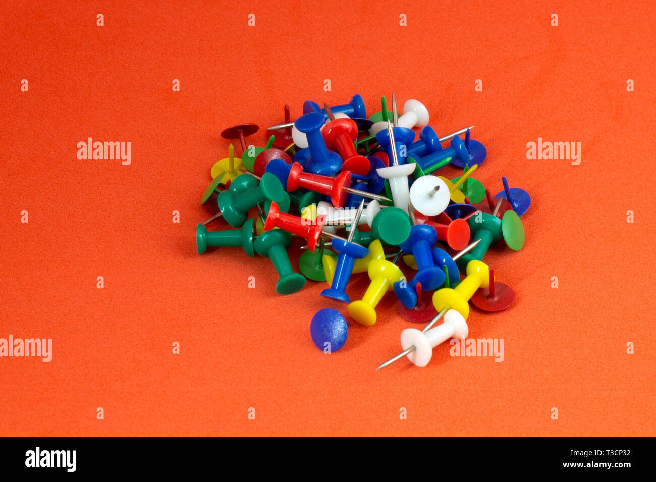 color push pins on orange background Stock Photo - Alamy