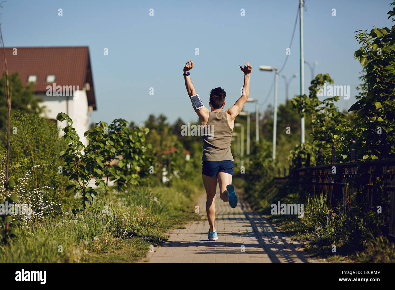 A male runner runs with his arms raised in the park Stock Photo - Alamy