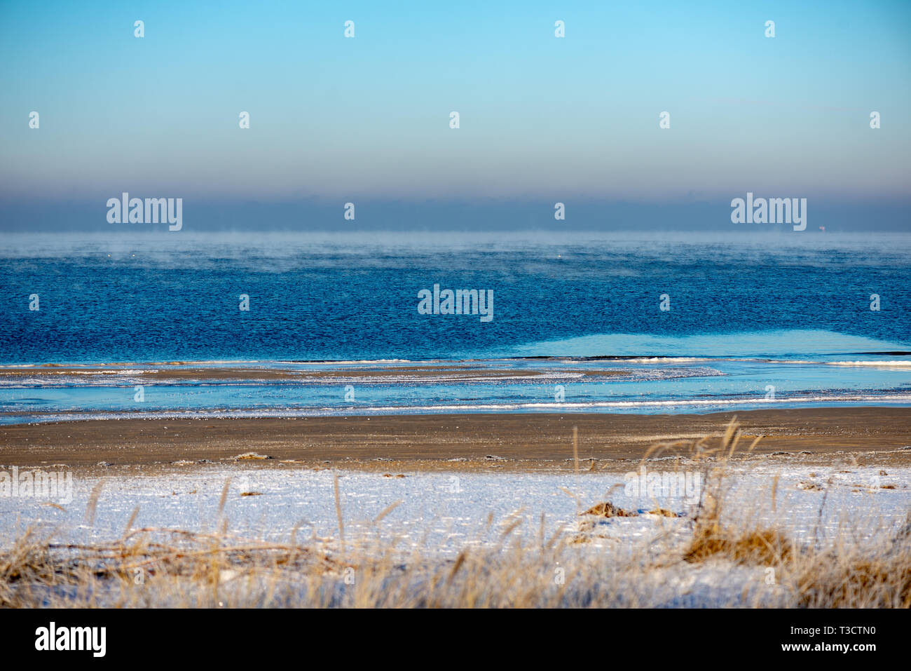 frozen sea beach in winter with low snow coverage. ice in sunny day on ...