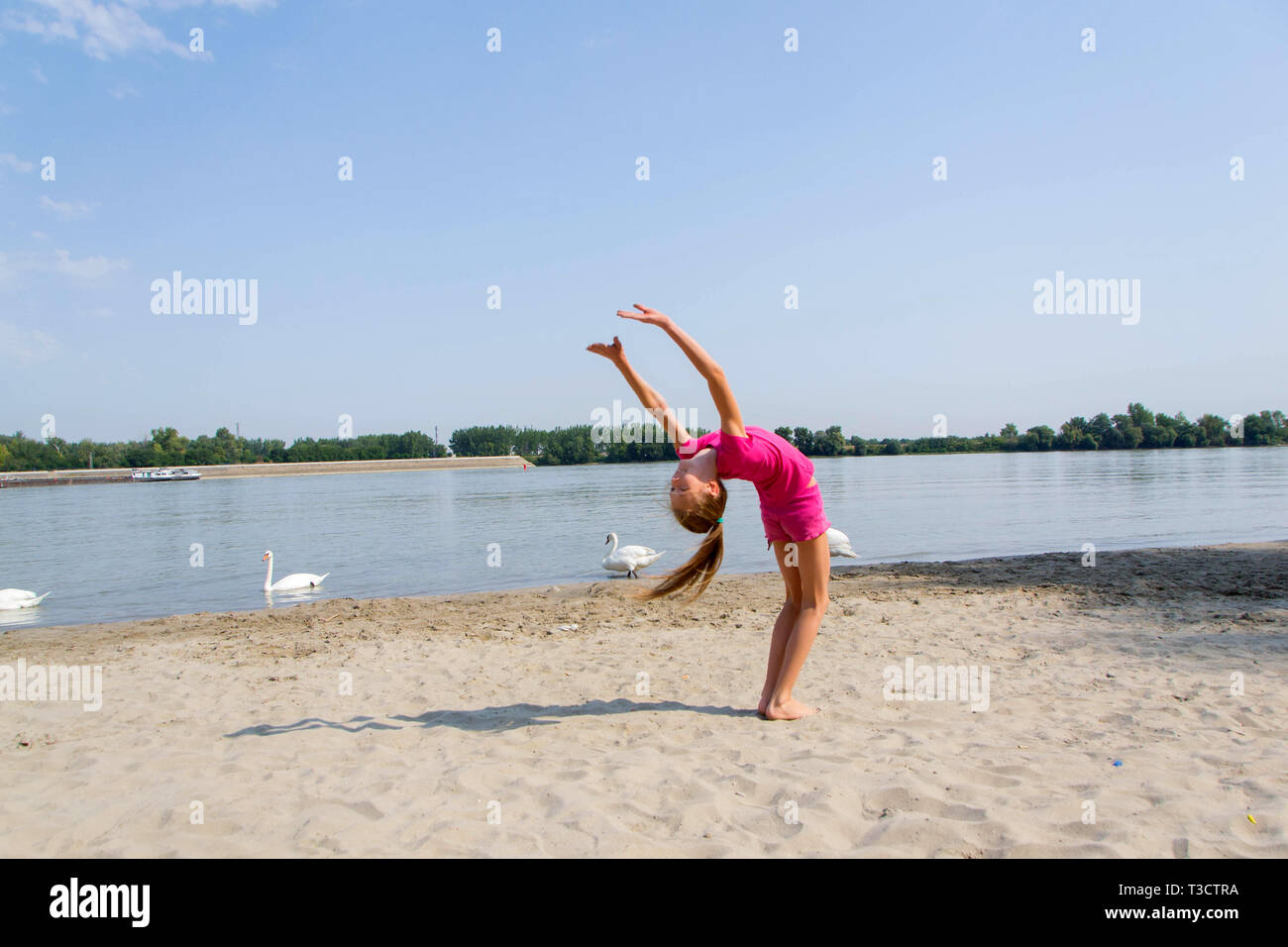 Young athletic girl makes gymnastic figures on the beach Stock Photo ...