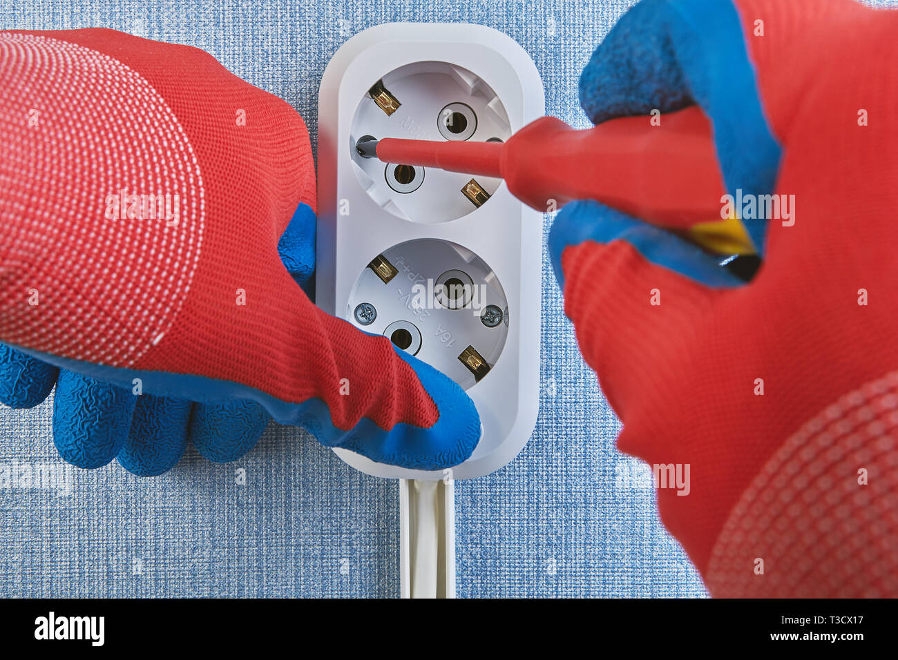 Tightening screws by screwdriver during installing wall plug socket ...