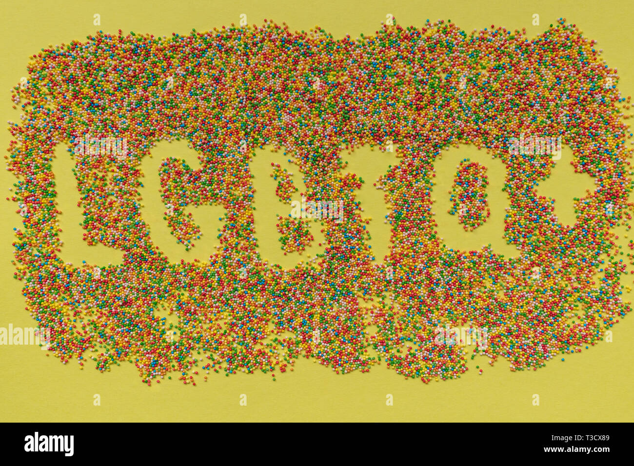 LGBTQ word and plus sign written in sprinkles on a yellow background ...