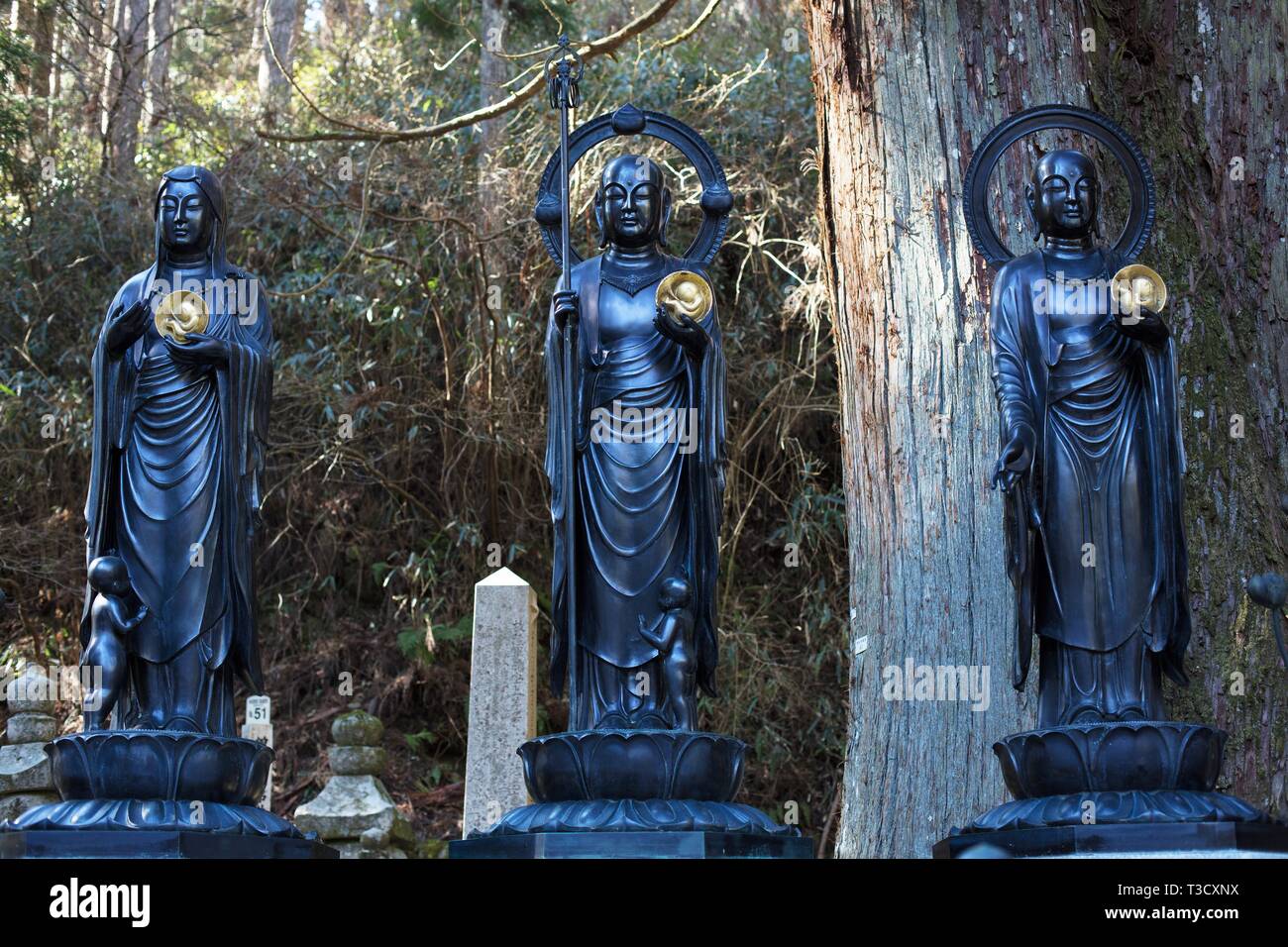 Three black robed statues holding golden fetuses in Okunoin cemetery in ...