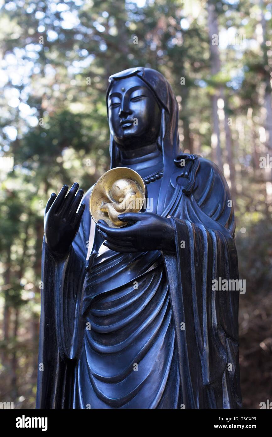 A black statue of Buddhist holding golden fetus, in Okunoin cemetery in ...