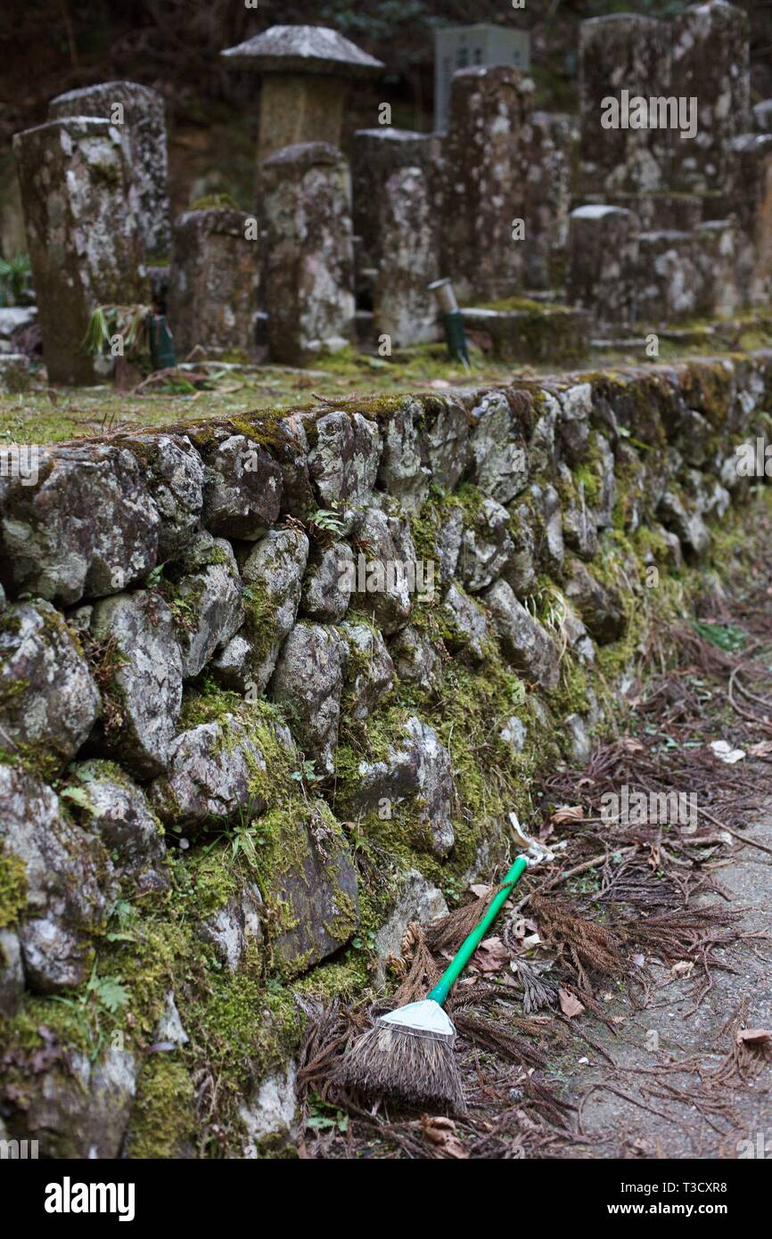 A broom lying on the ground next to mossy old grave markers in Okunoin ...