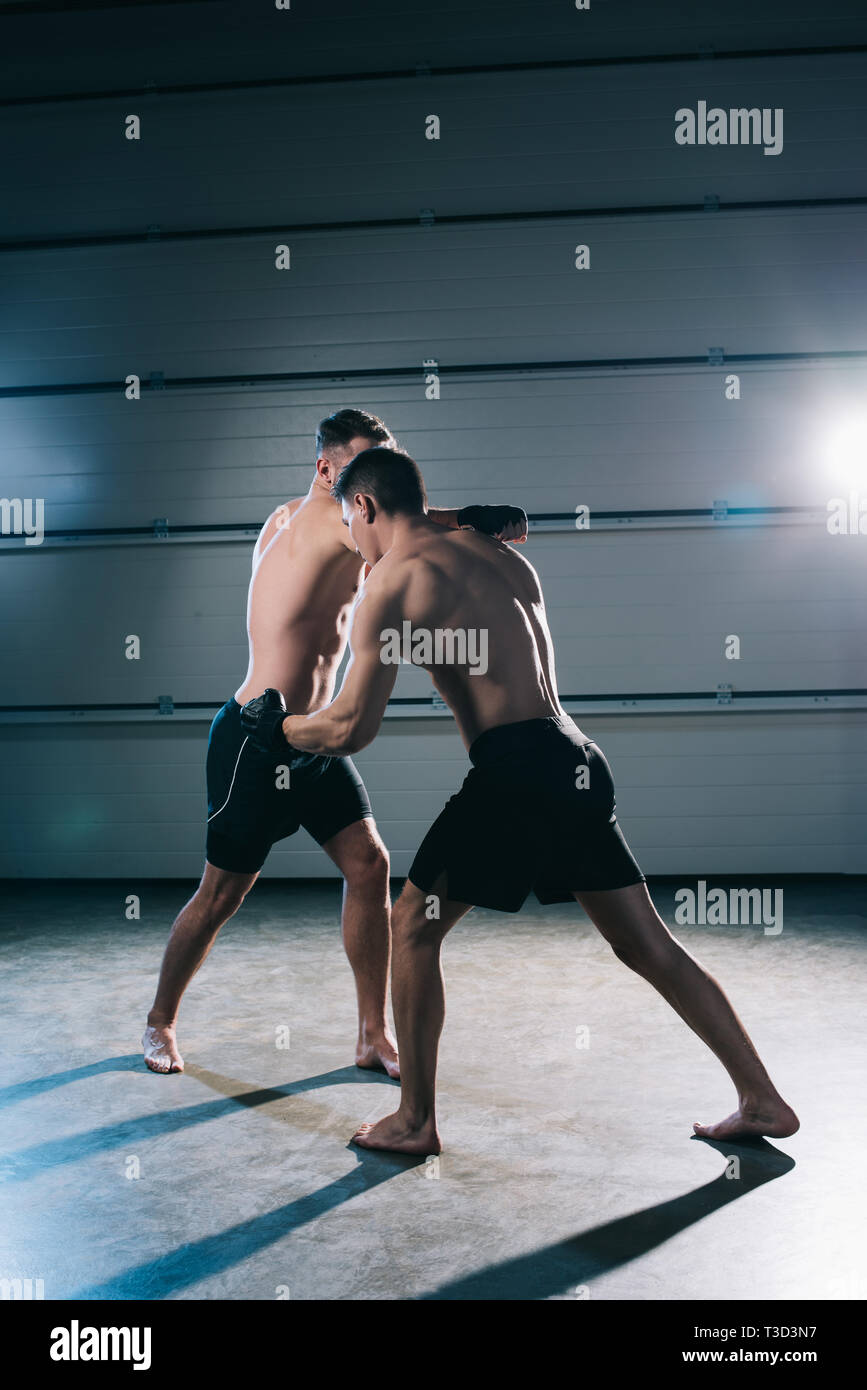 strong shirtless mma sportsmen fighting while man punching with arm ...