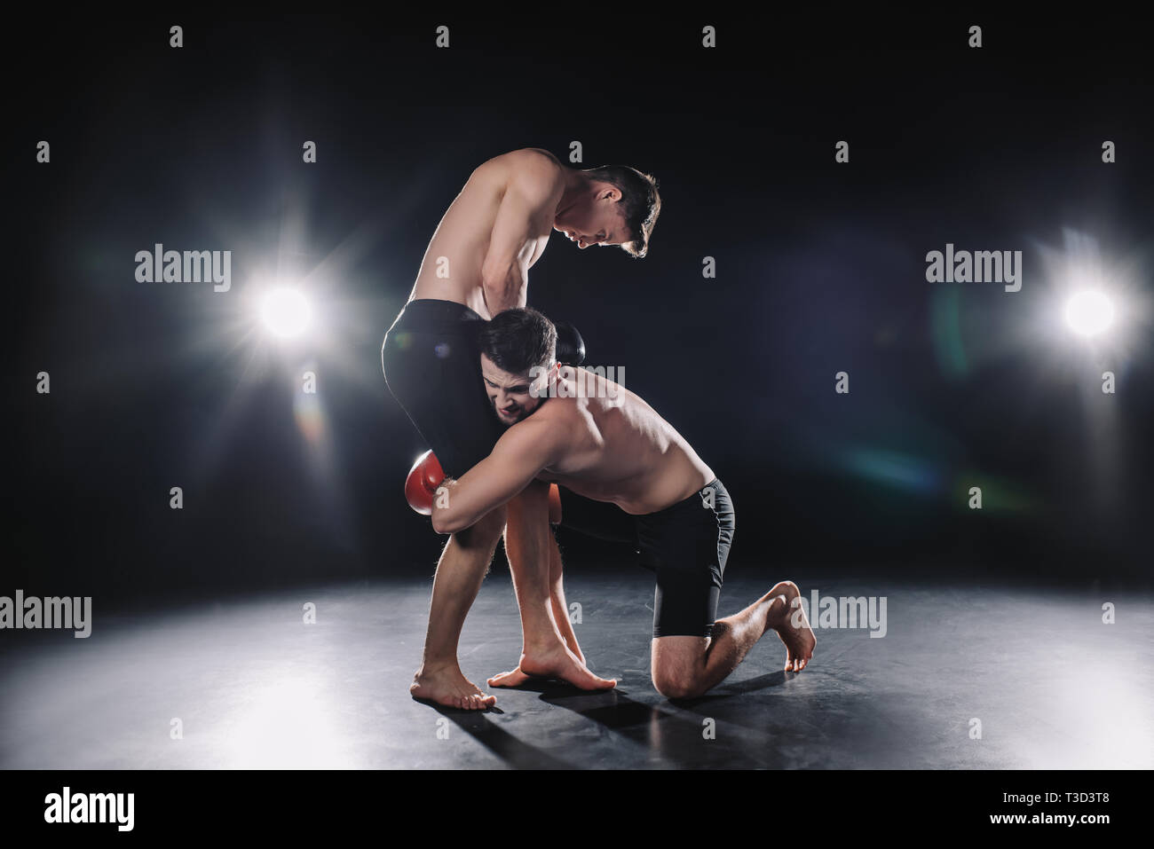 barefoot strong muscular mma fighter in boxing gloves clinching another ...