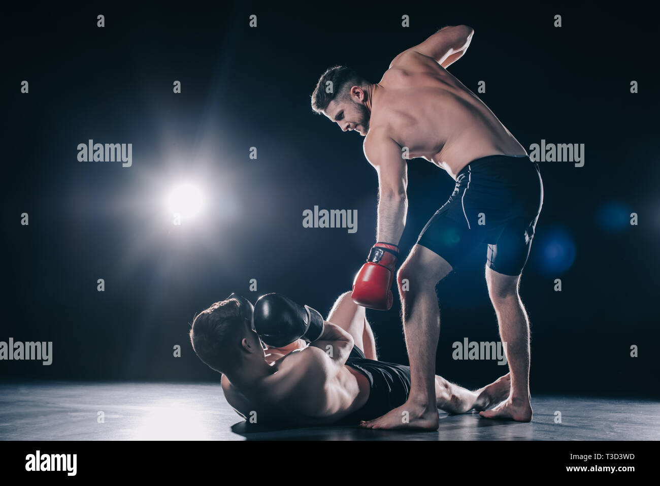 shirtless strong mma fighter in boxing gloves standing above opponent ...