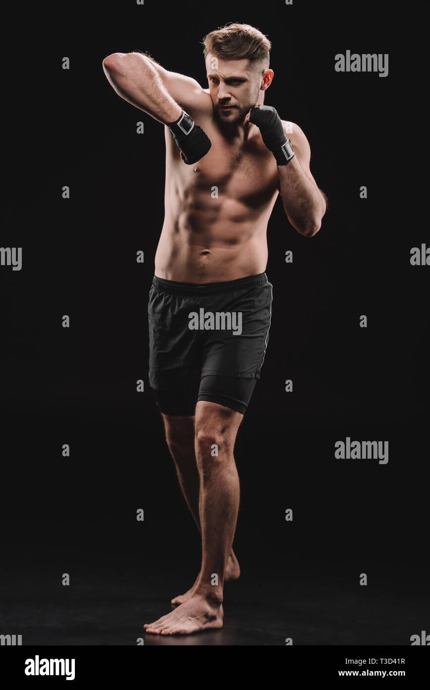 muscular mma fighter in bandages doing punch with elbow on black Stock ...