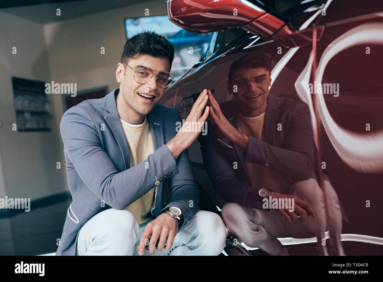 happy stylish man in glasses sitting near red automobile Stock Photo ...