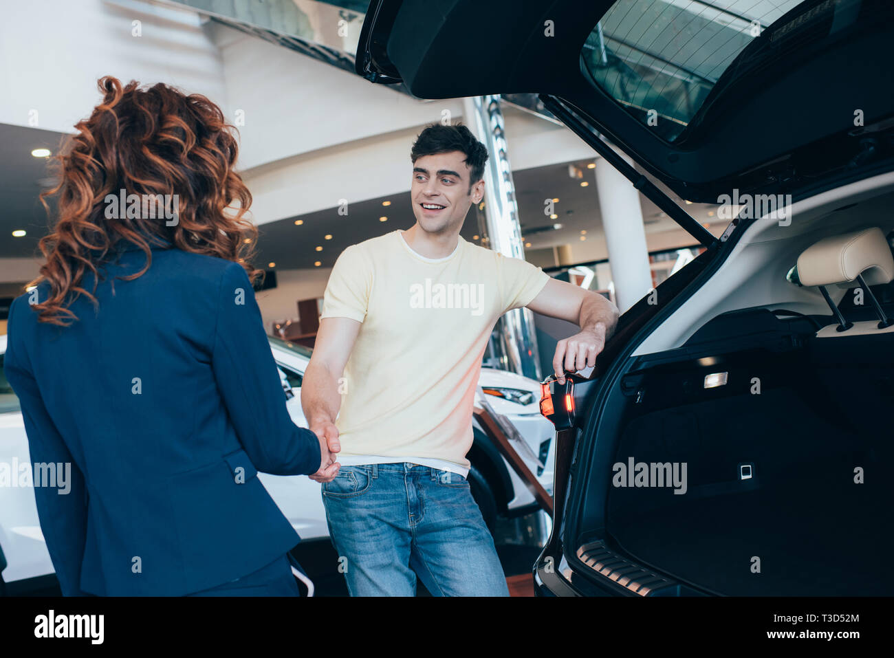 selective focus of happy man and car dealer shaking hands in car ...