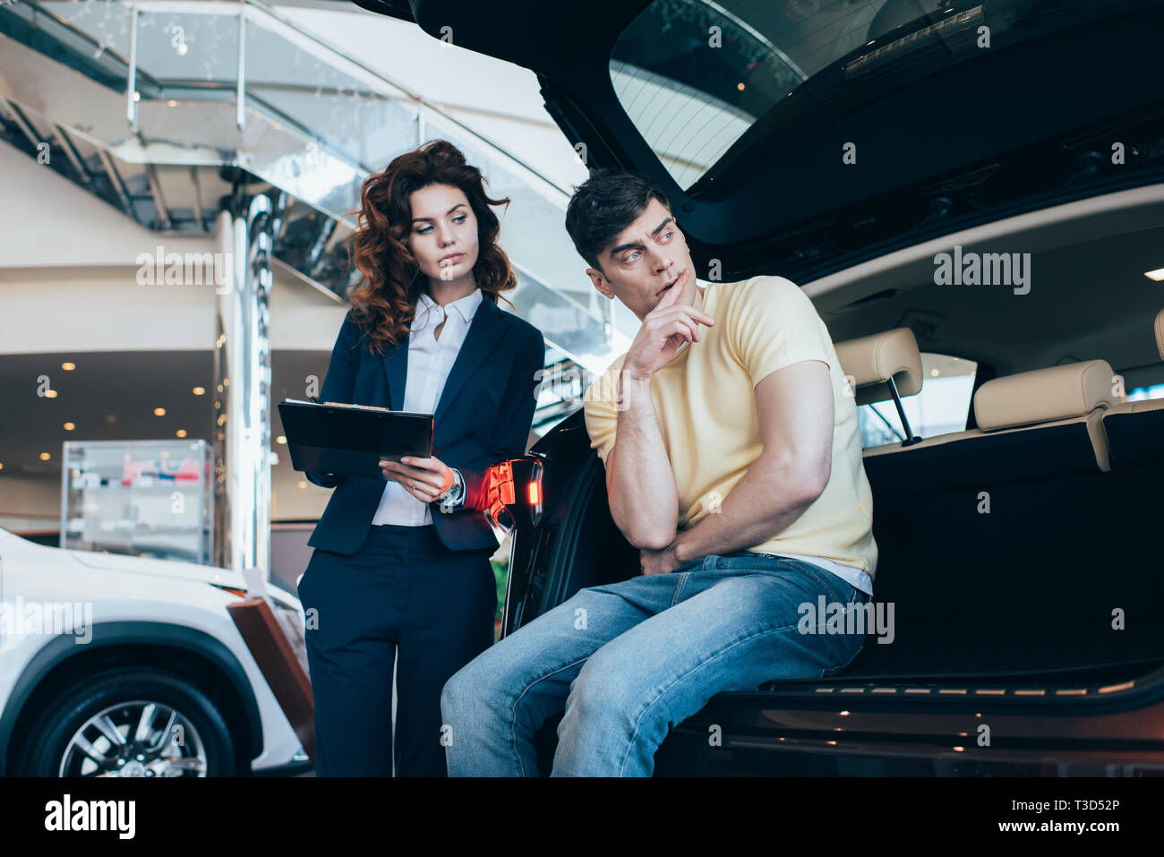 serious car dealer and customer near new car in car showroom Stock ...