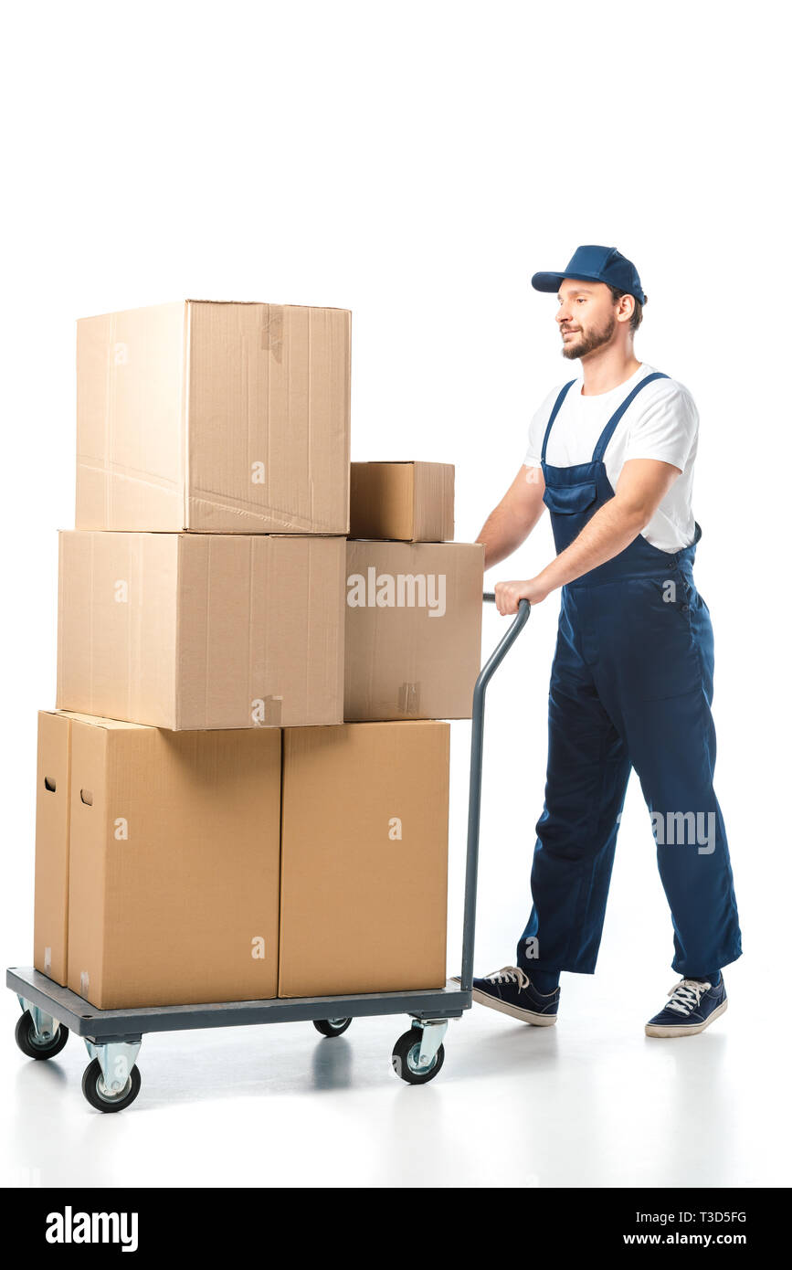 handsome mover in uniform transporting cardboard boxes on hand truck ...