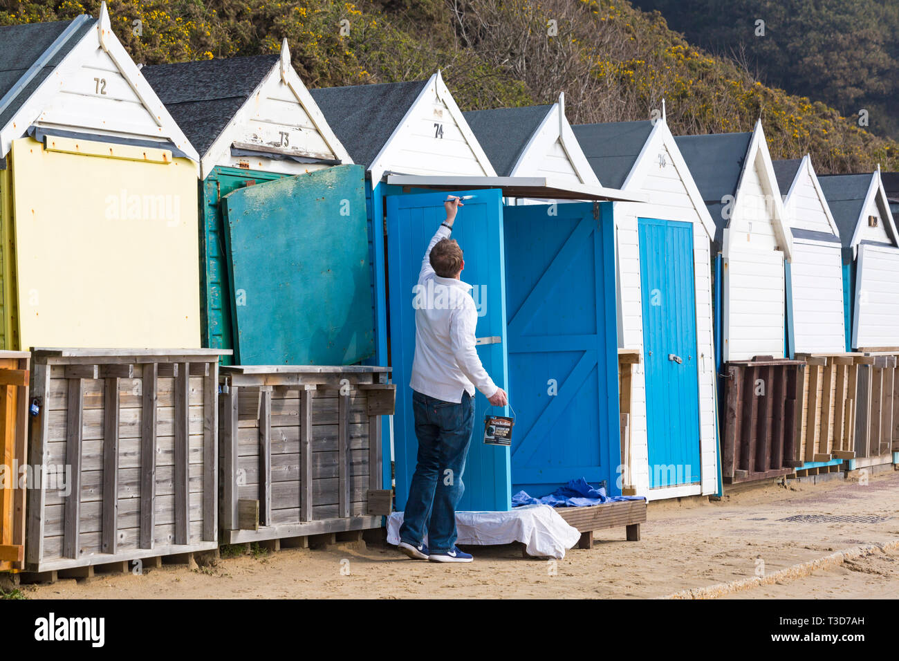 Man painting beach hut at Middle Chine, Bournemouth, Dorset UK in April ...