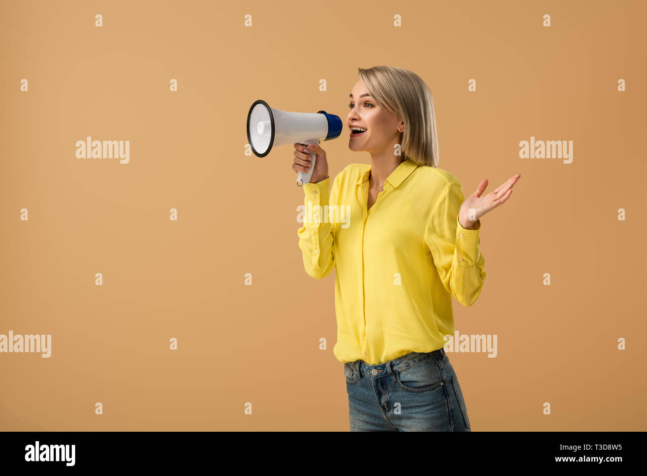 Smiling blonde woman in yellow shirt screaming in megaphone isolated on ...
