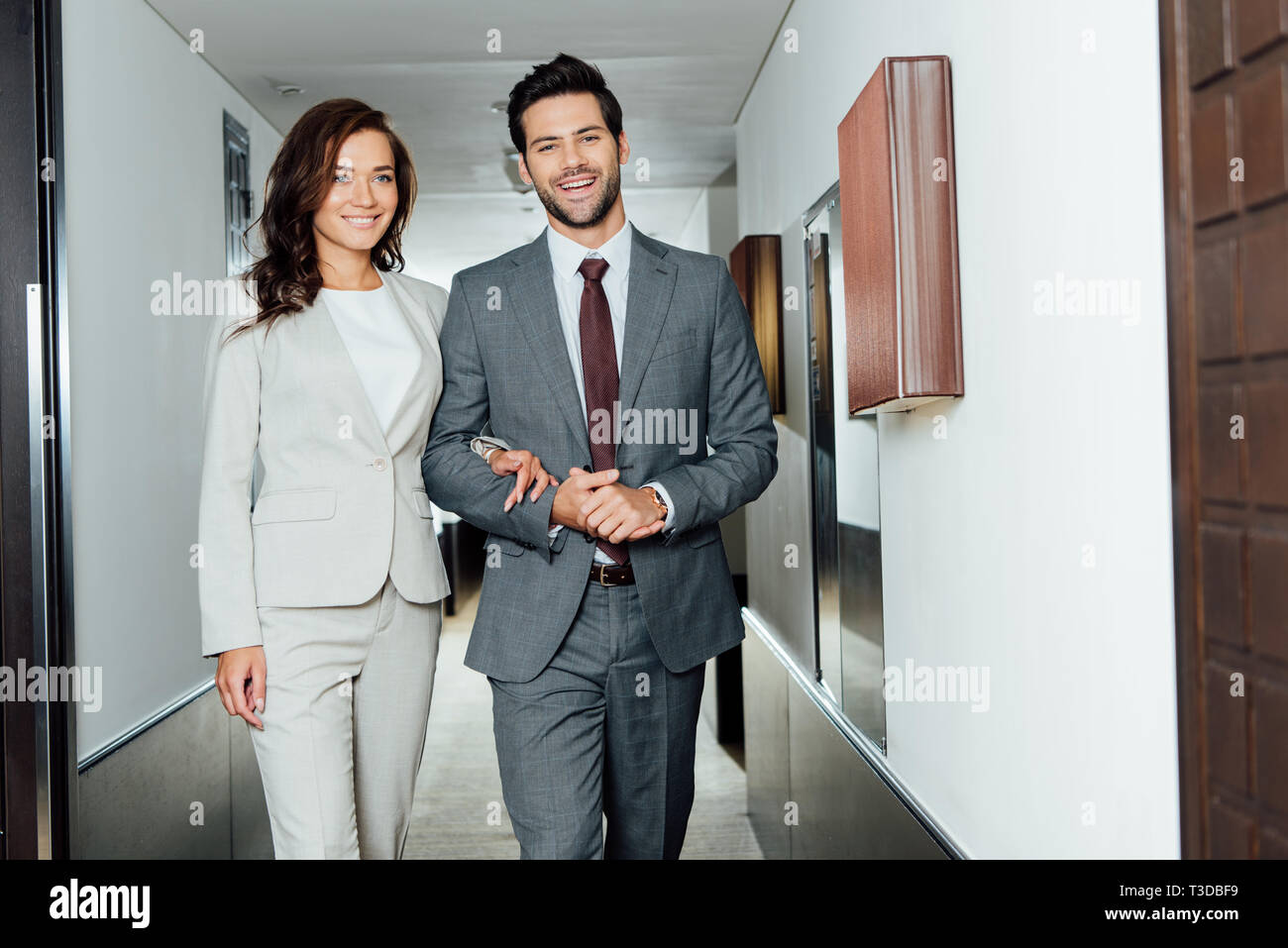 happy businessman and businesswoman in formal wear walking hotel ...