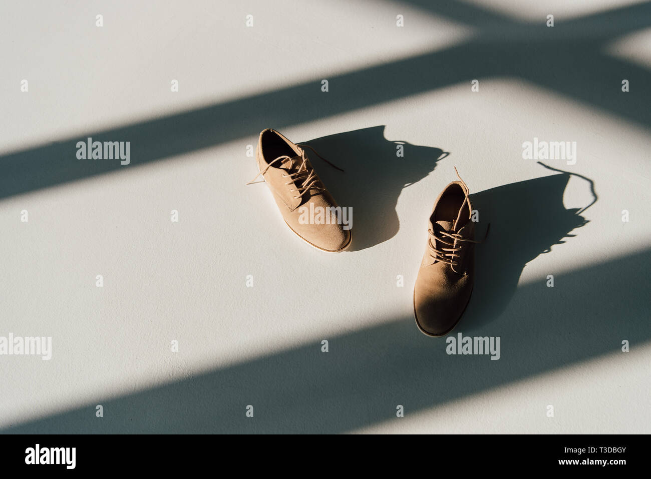 pair of beige suede shoes on floor in sunlight with shadows Stock Photo ...