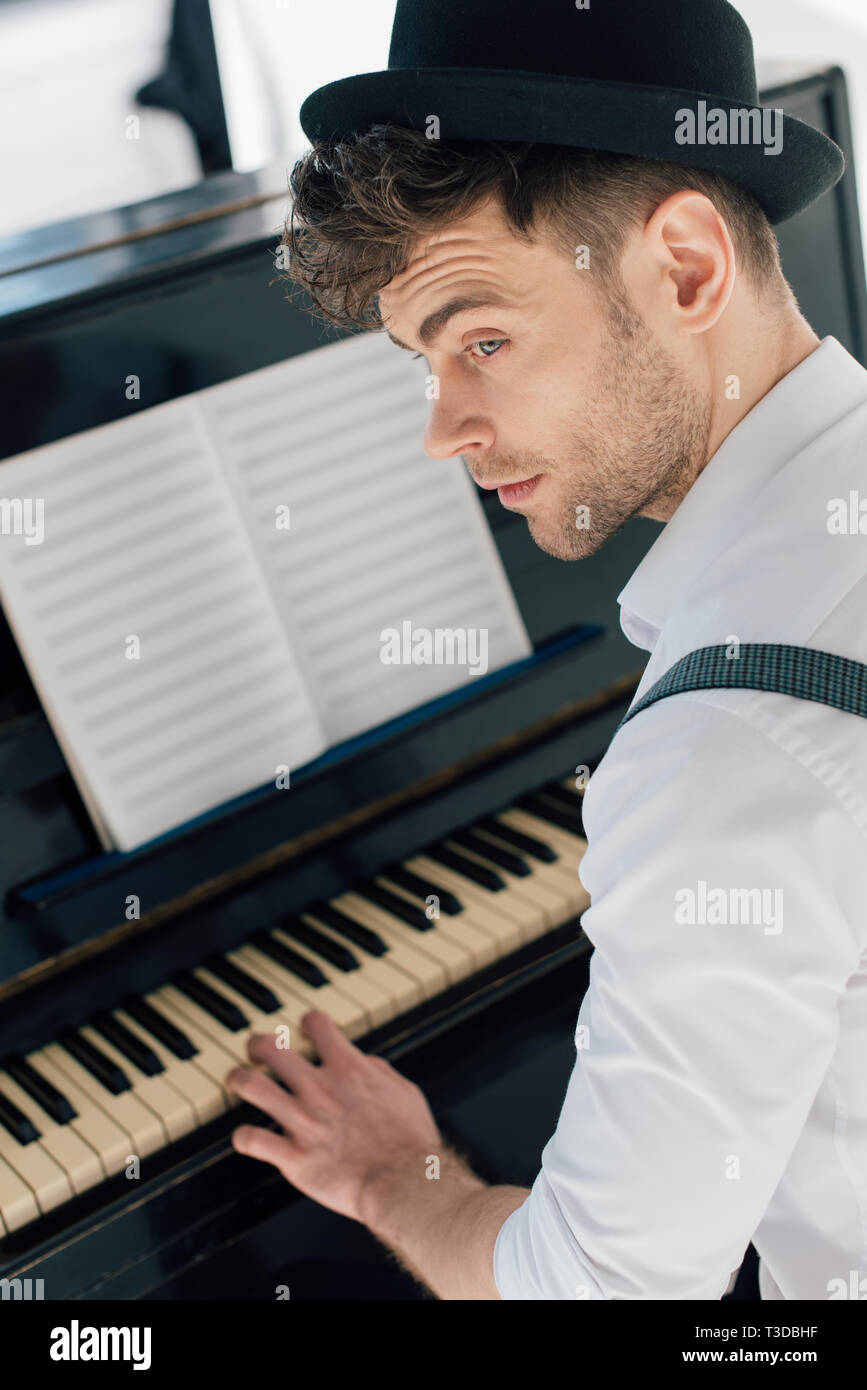 selective focus of good-looking pianist in stylish clothing playing ...