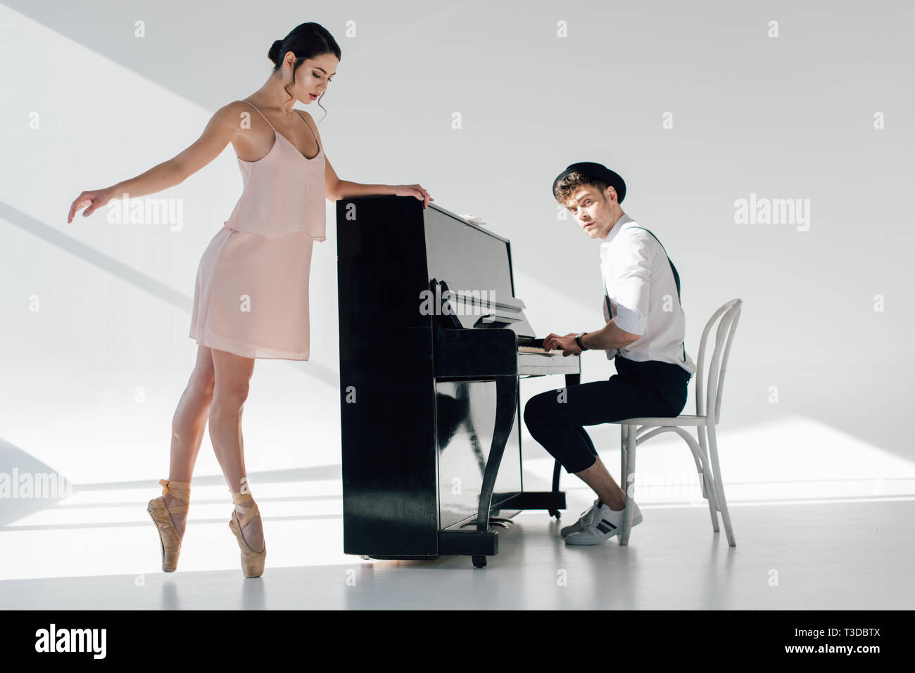 handsome pianist playing while beautiful ballerina dancing near piano ...