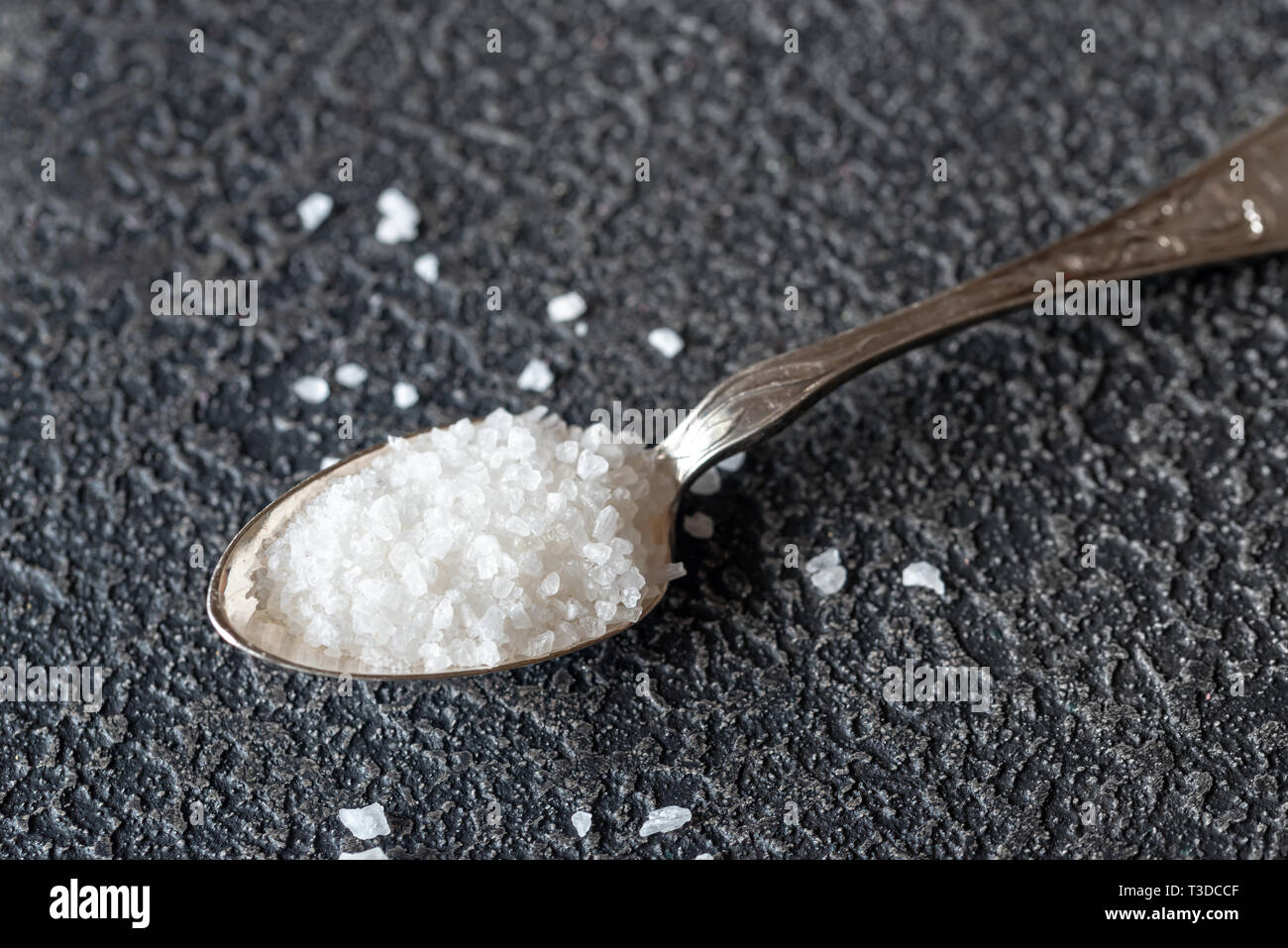 Silver spoon of sea salt on the dark background Stock Photo - Alamy