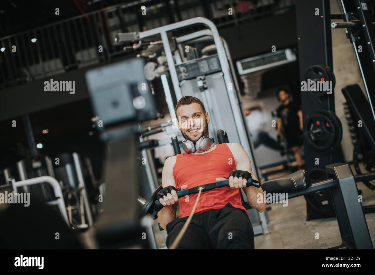 Athletic man doing workouts on a back with power exercise machine in a ...