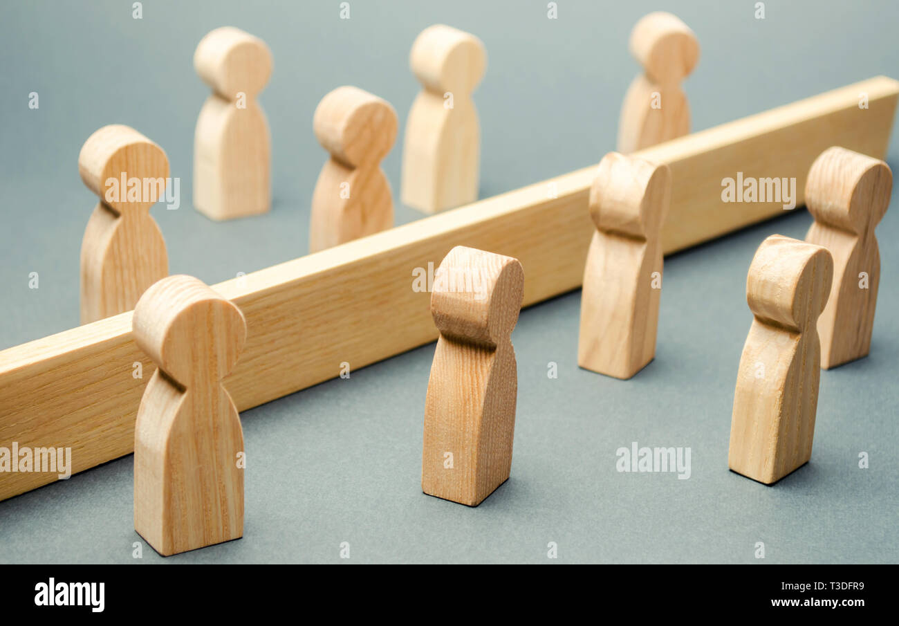 Wooden figures of people are separated by a barrier. Social classes ...