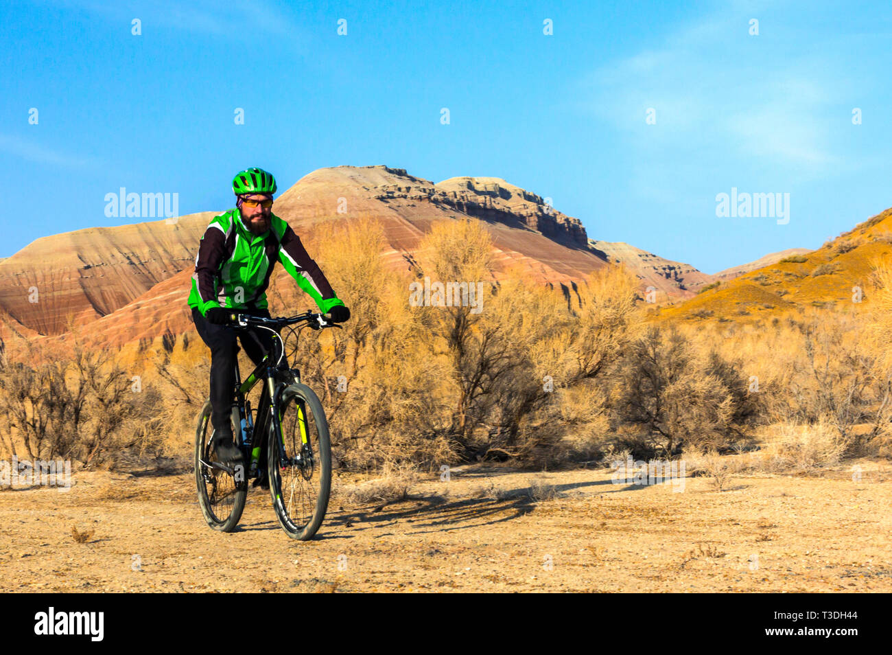 Young man on a bicycle. A trip through the desert territory. Cyclist in ...