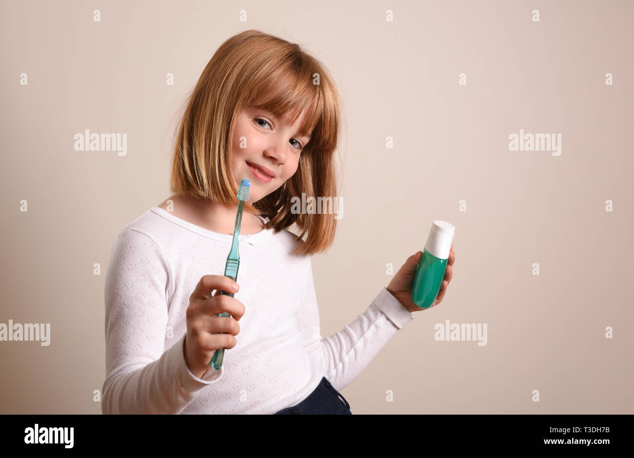 Girl showing toothbrush and toothpaste on brown isolated background ...