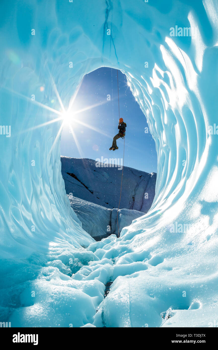In the backcountry of Alaska, an ice climber rappels into an ice cave ...