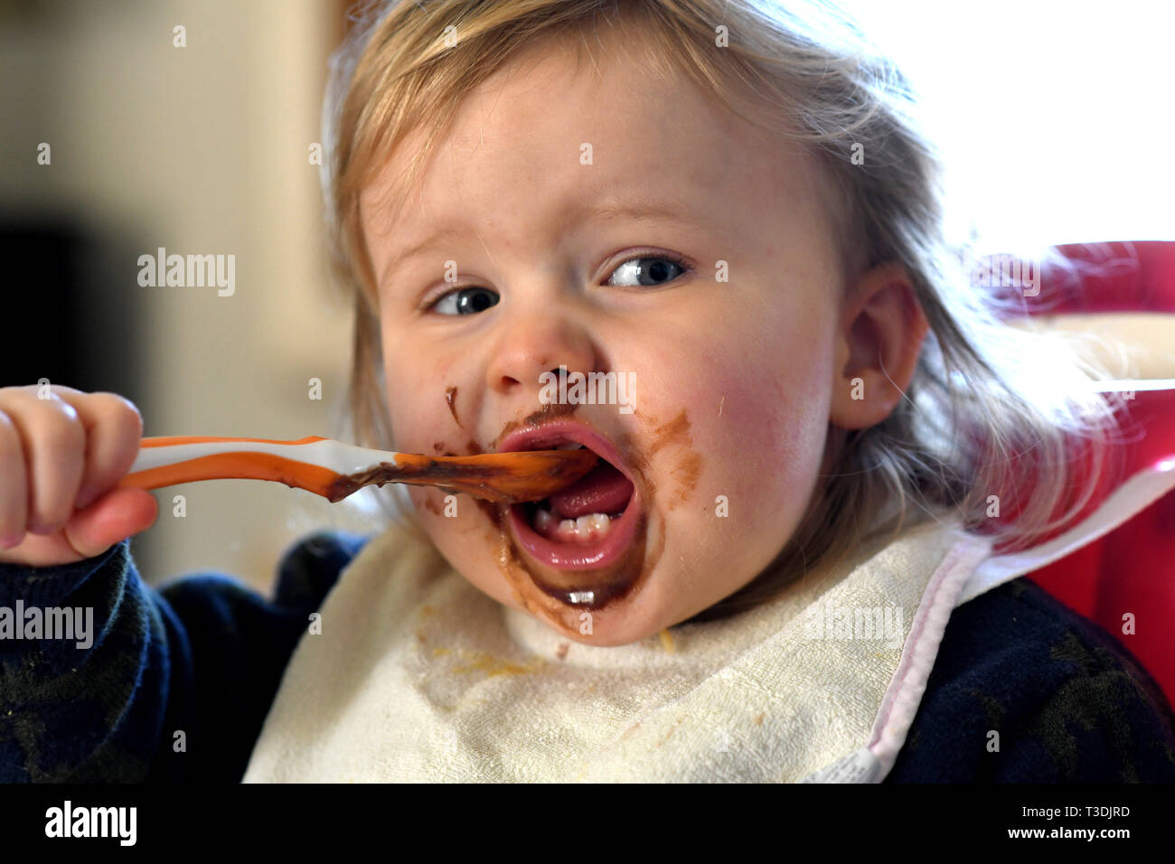 Baby girl feeding herself with chocolate on her face Stock Photo - Alamy