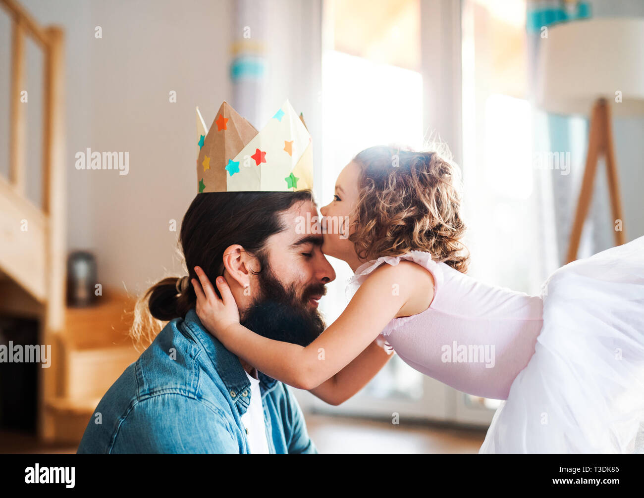 A side view of small girl with a princess crown and young father at ...