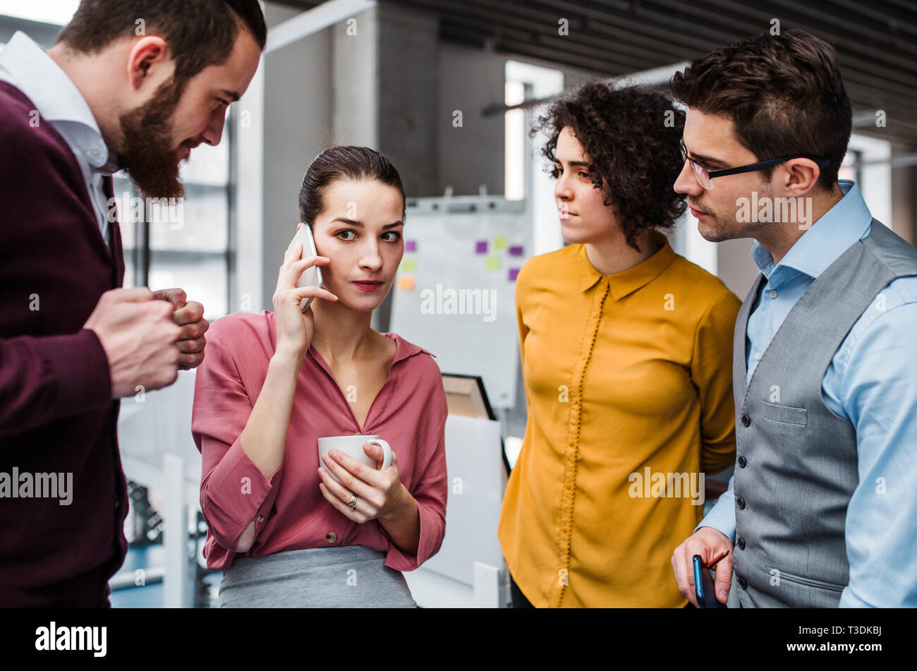 A group of young businesspeople with smartphone standing in office ...