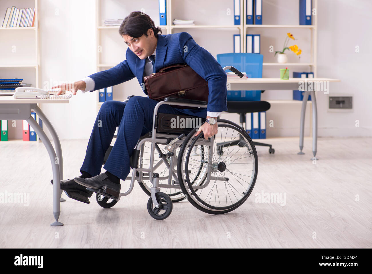 Young male employee in wheelchair working in the office Stock Photo - Alamy