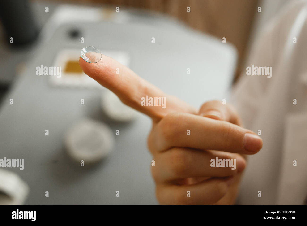 Female finger with contact lens on blurred background. Doctor in ...