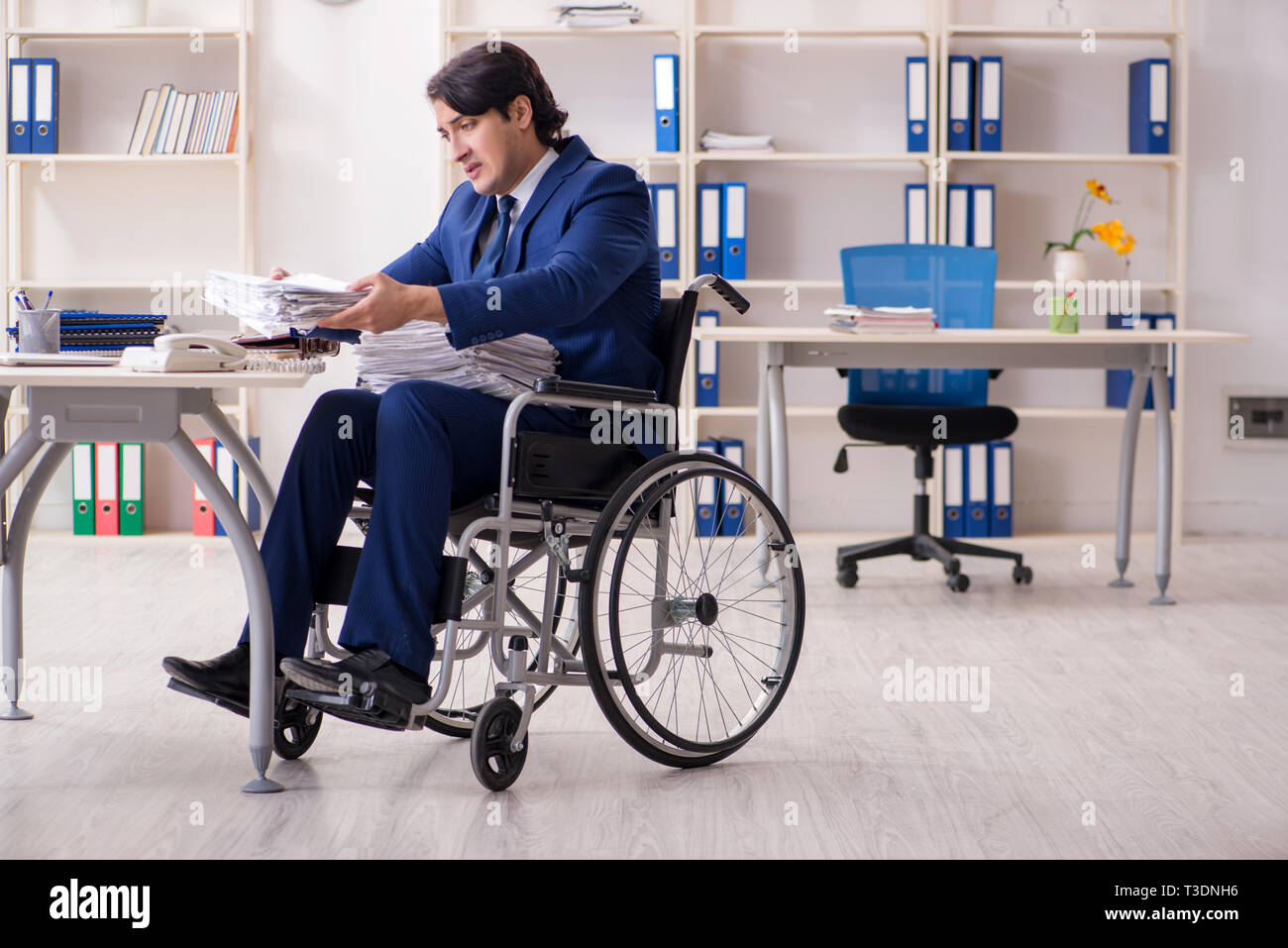 Young male employee in wheelchair working in the office Stock Photo - Alamy