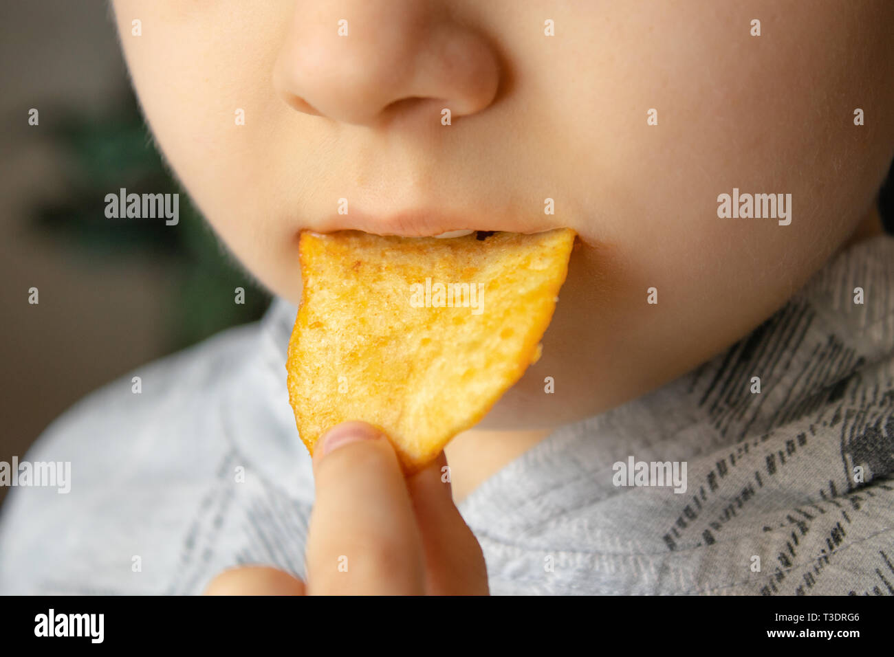Baby eating chips. Close-up. The child holds the chips. Junk food Stock ...