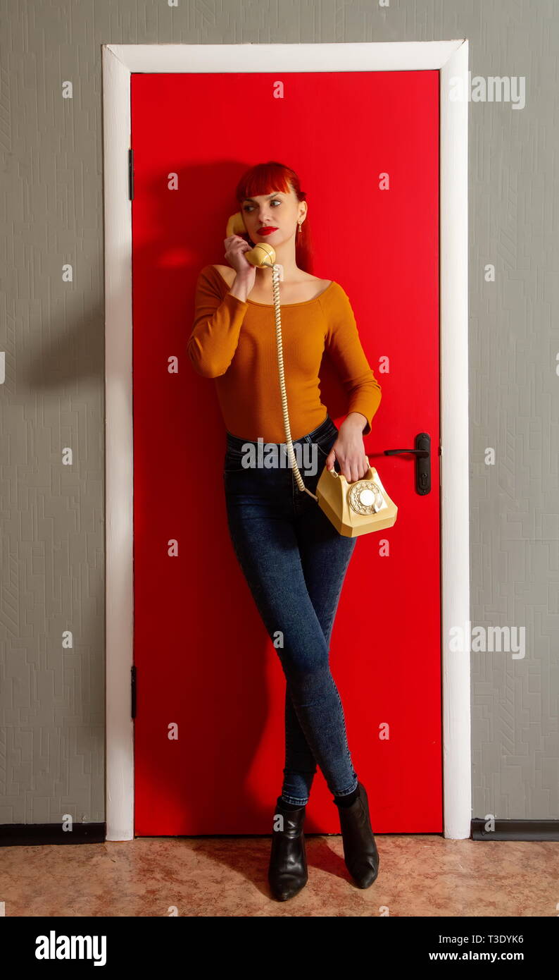 Pretty woman talking on an old dial telephone with a twisted wire on ...